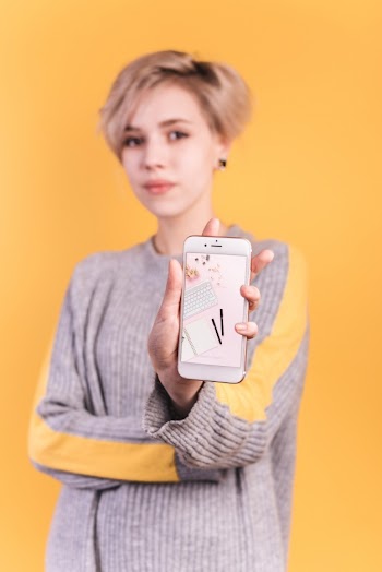 Free: Cheerful Young Woman Holding Smartphone in Studio - nohat.cc